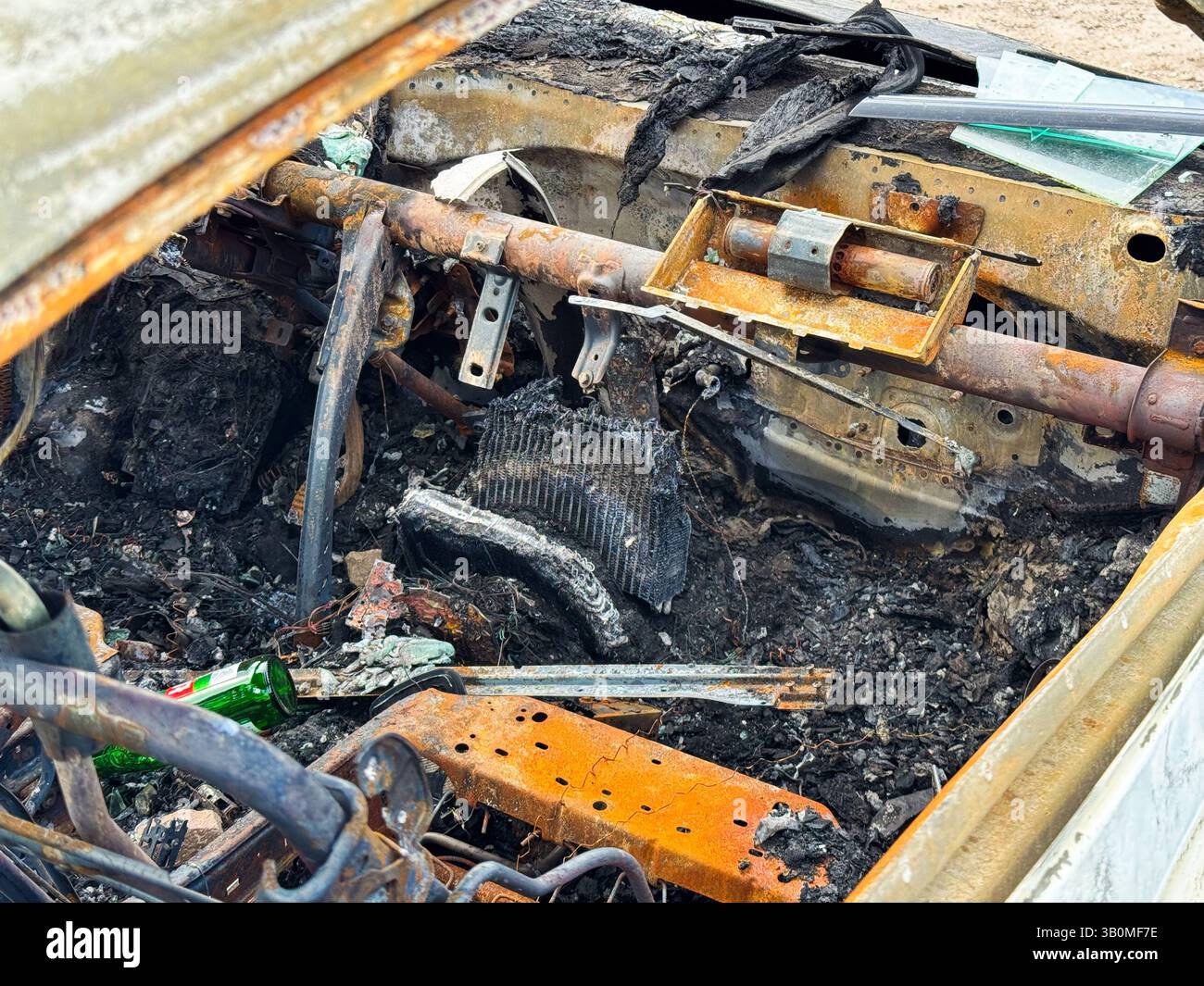 Detailed view of a burned car's dashboard area with rusted metal ...