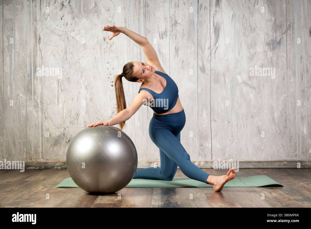 Pregnant athlete performing side bend exercise using fitball on yoga ...