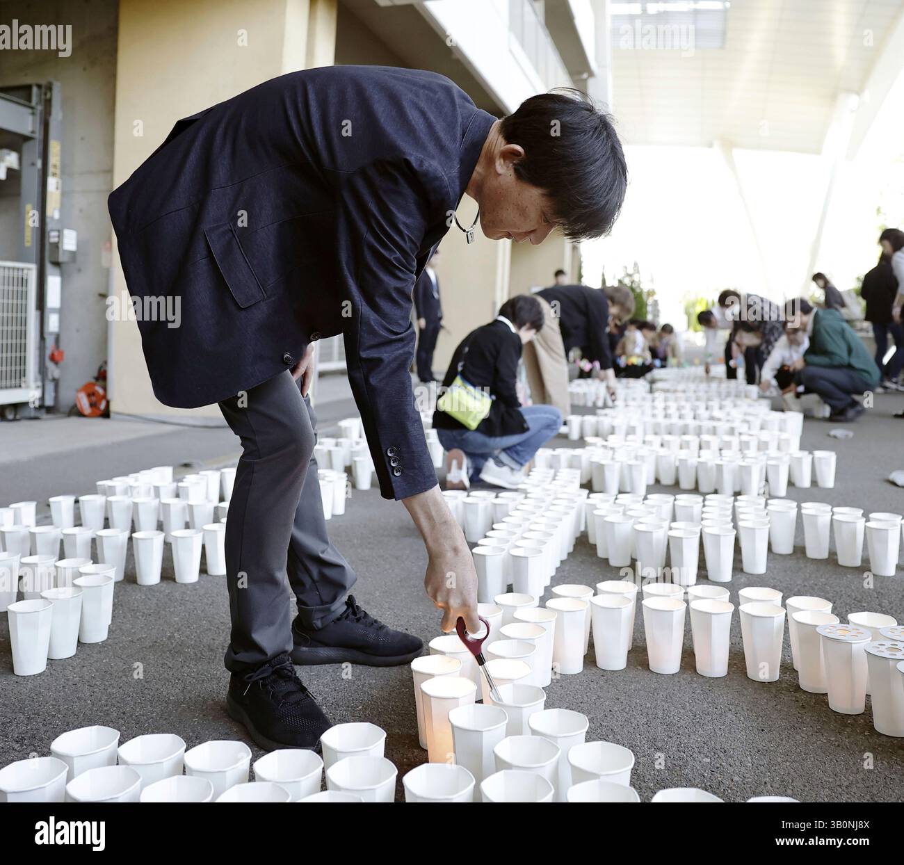People prepare candles for a memorial event for the JR Fukuchiyama Line derailment at the site ...