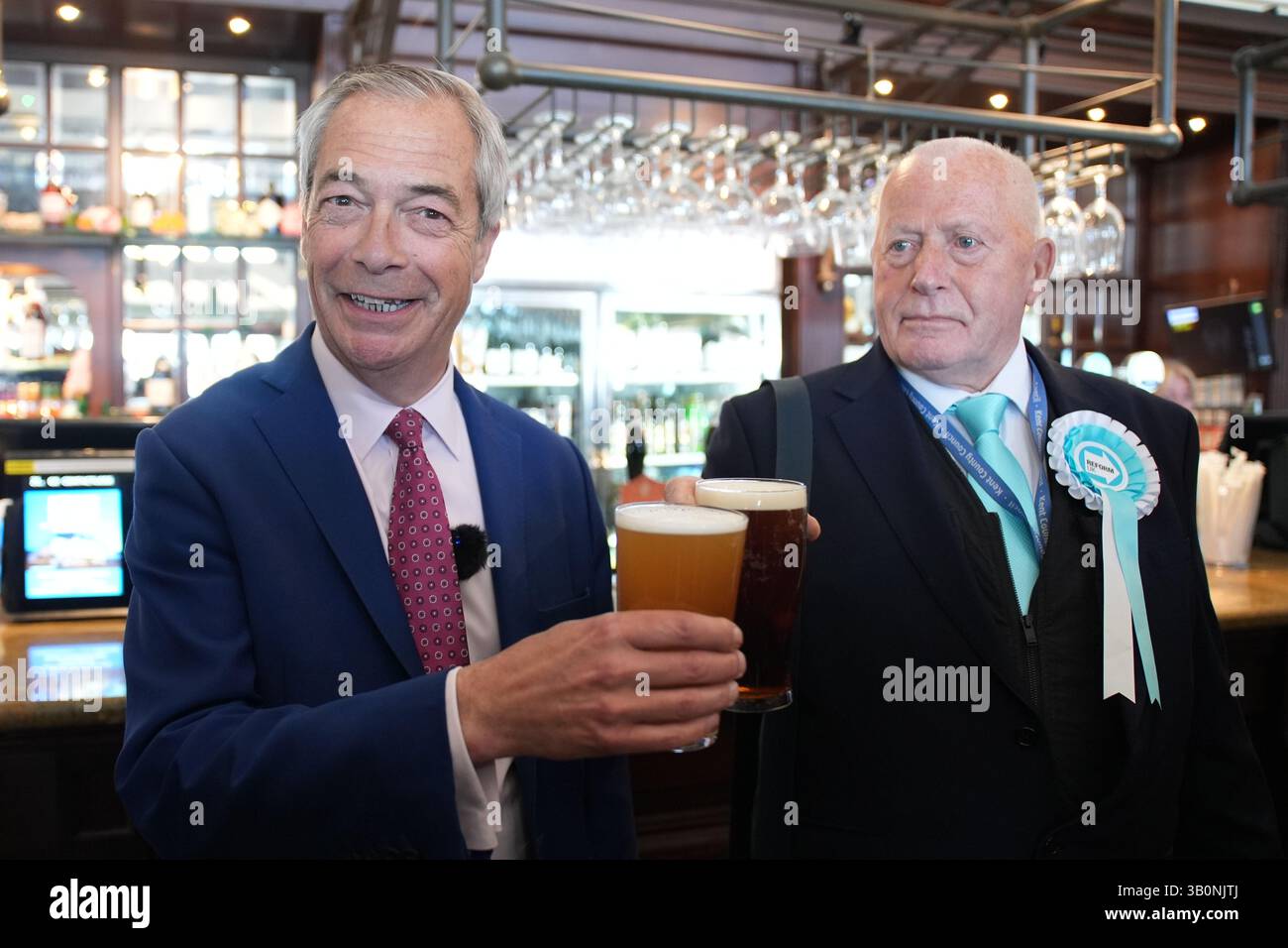 Reform UK leader Nigel Farage (left) has a drink during a visit to the ...