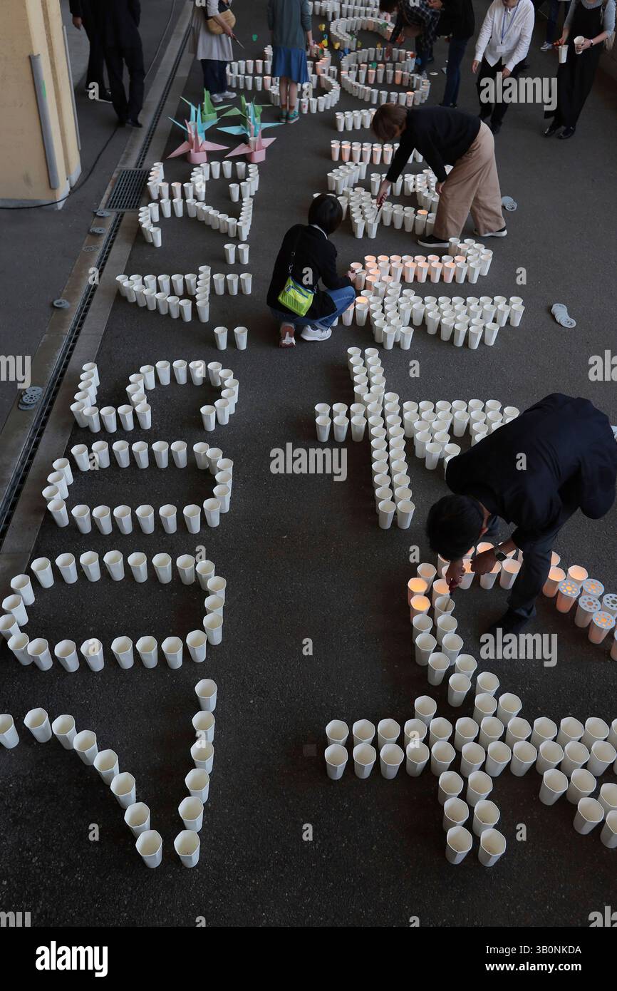 People prepare candles for a memorial event for the JR Fukuchiyama Line derailment at the site ...