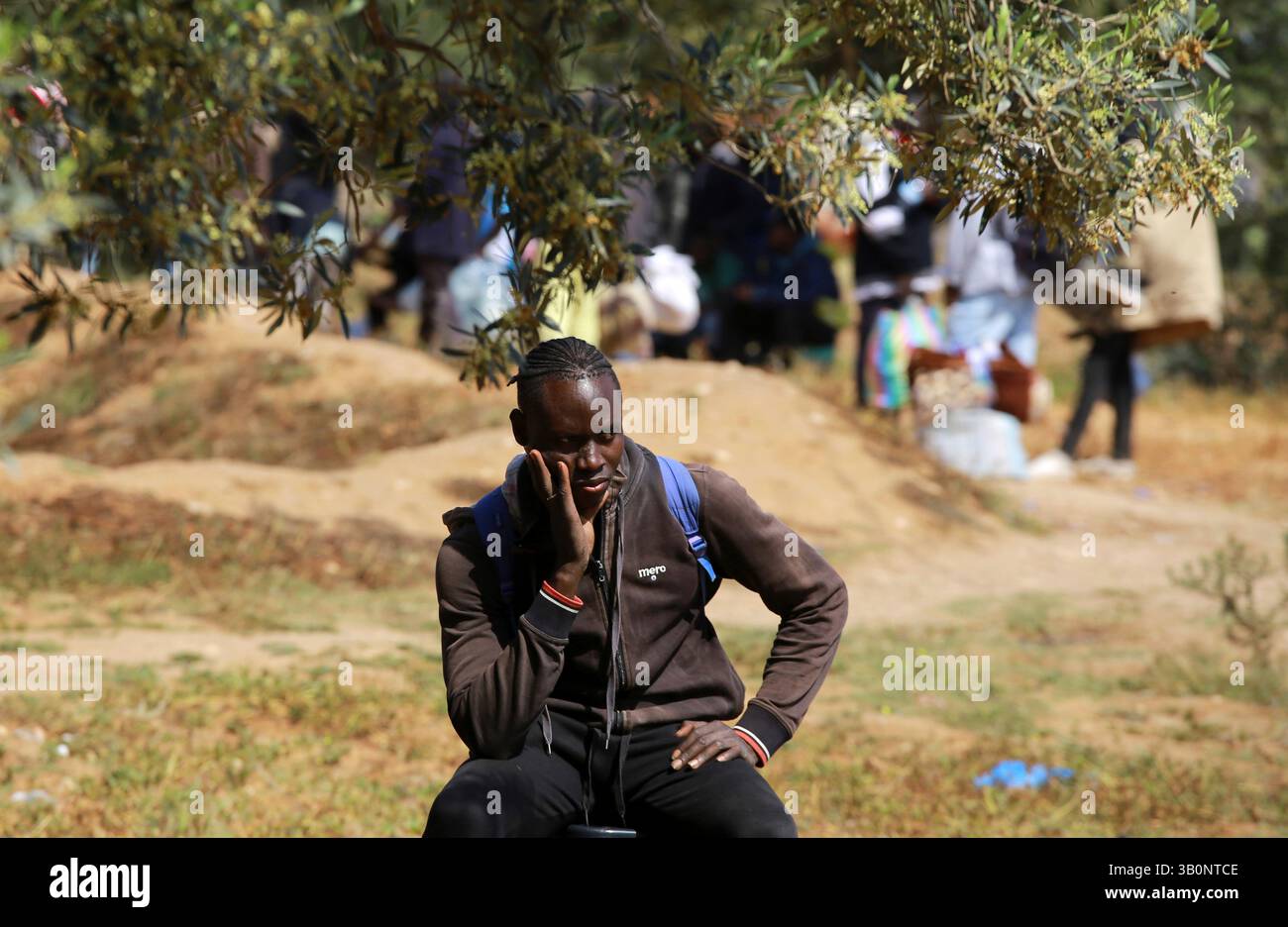 A Sub-Saharan migrant watches as a makeshift camp where he was staying ...