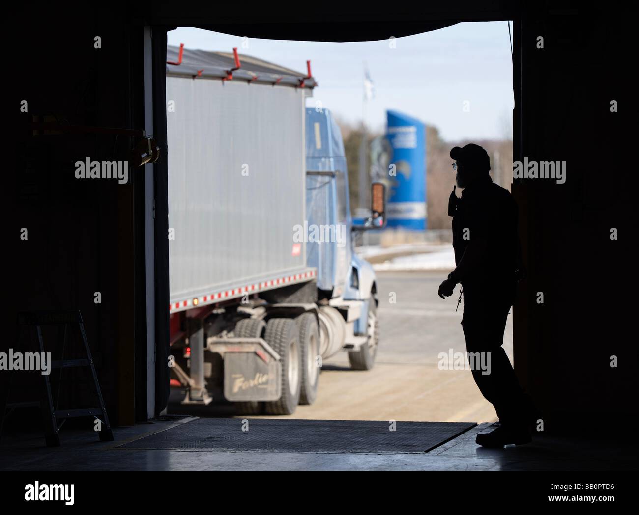 A Canada Border Services officer looks over at a truck as it waits to ...