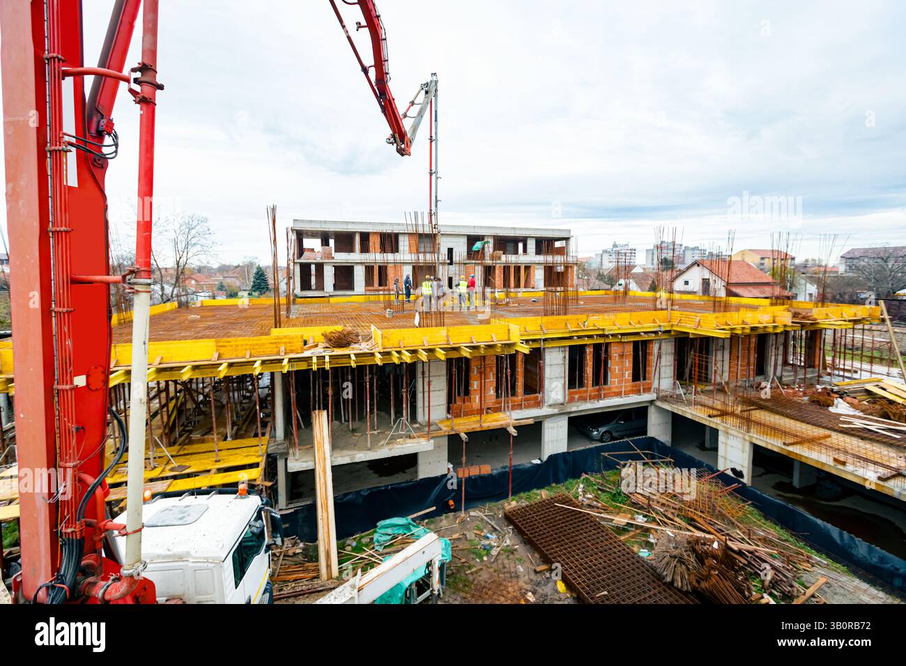 Truck with pump machine is standing, directing exit tube on wooden mold ...