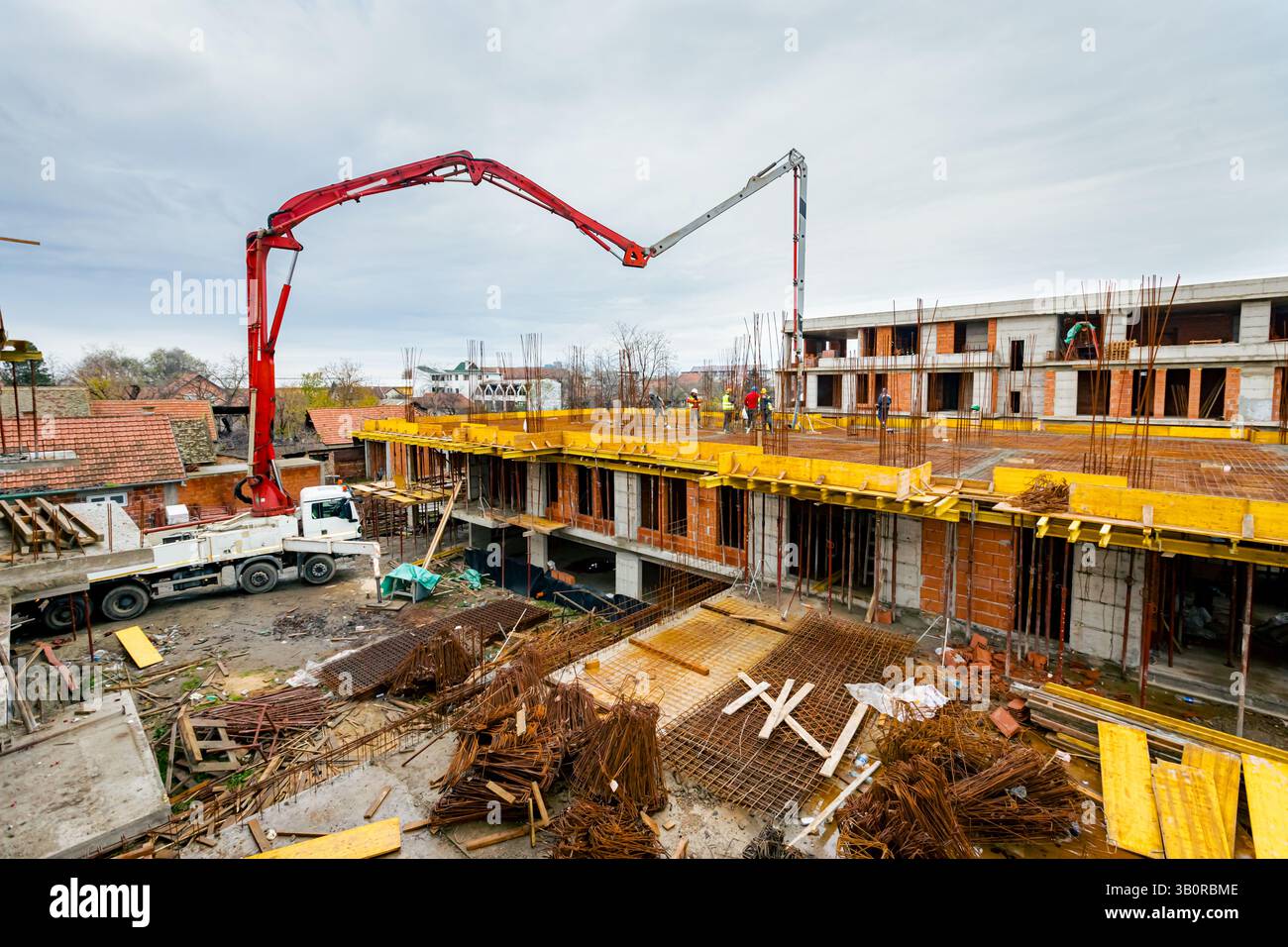 Truck with pump machine is standing, directing exit tube on wooden mold ...
