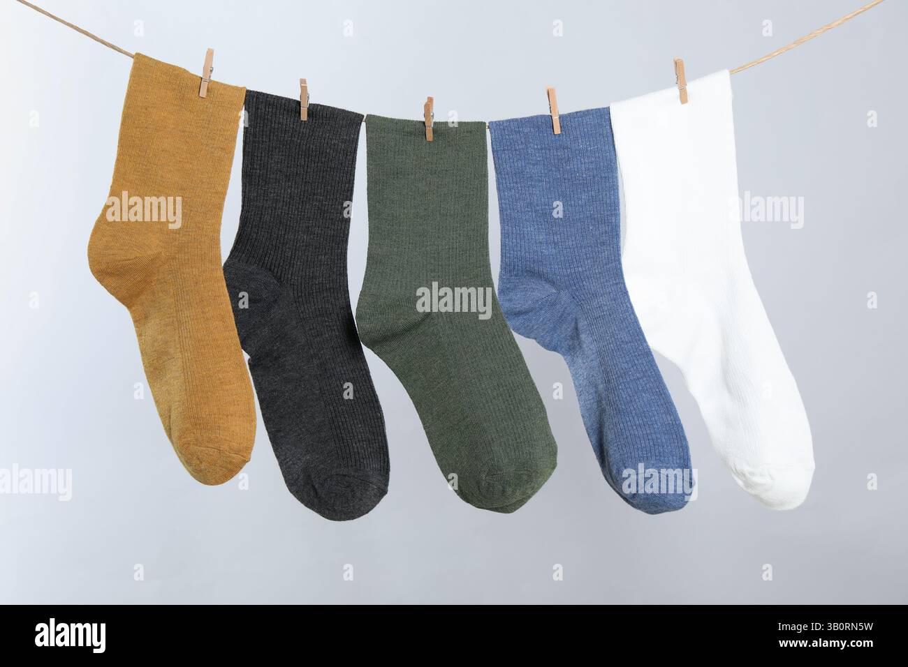 Different socks hanging on washing line against light grey background ...