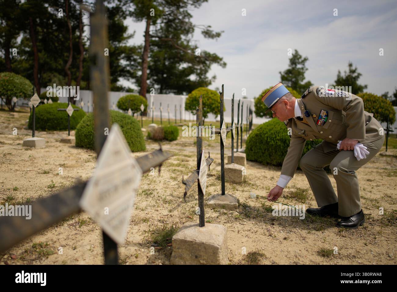 A French officer places a carnation on a grave of a countryman soldier ...