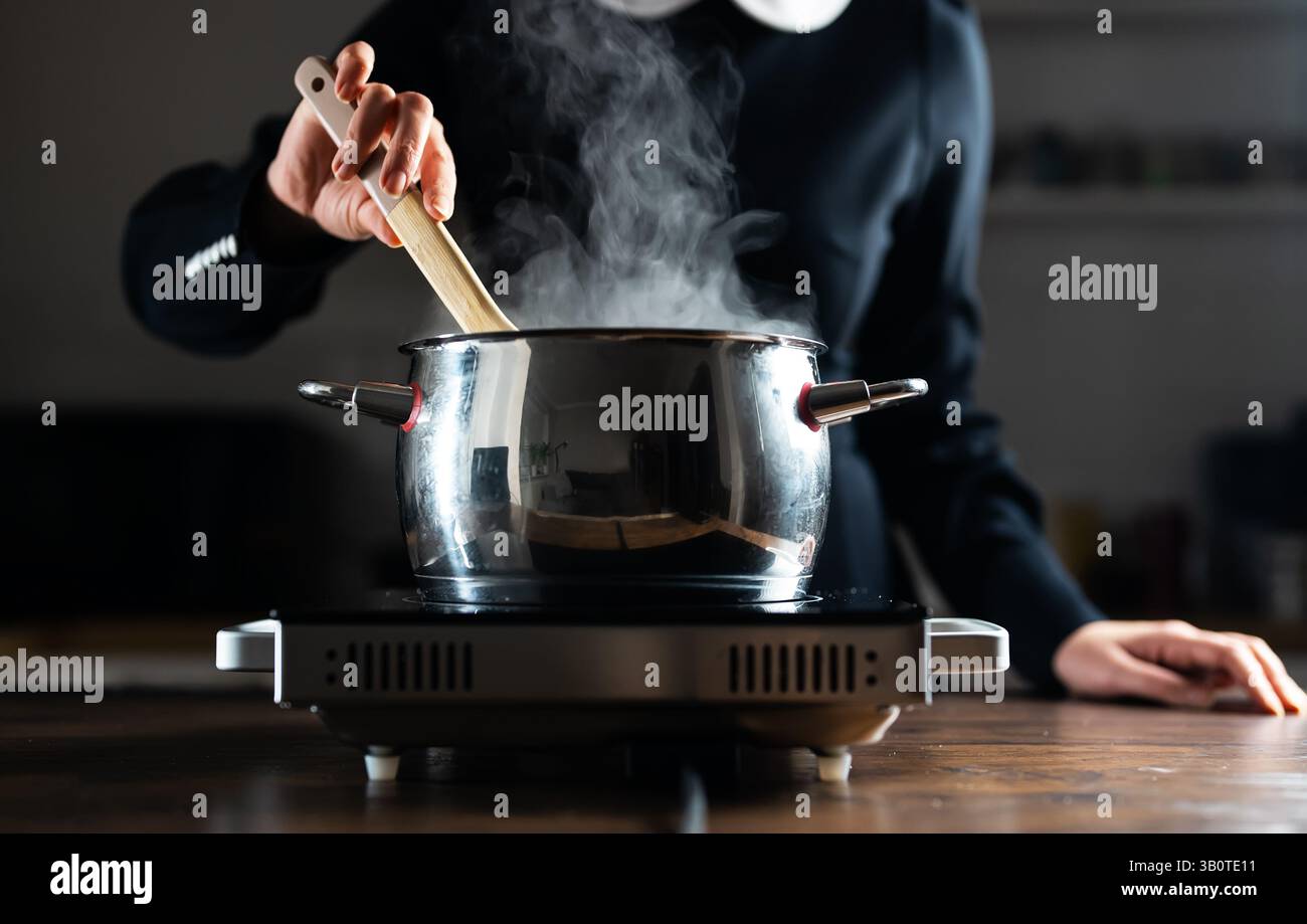Female chef cooking with steam rising from pot Stock Photo - Alamy