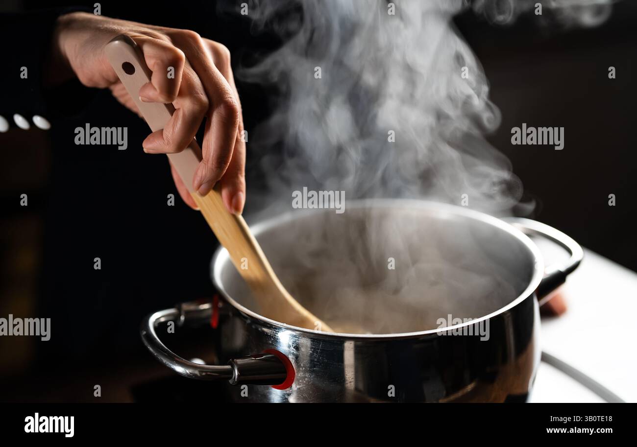 Female chef cooking with steam rising from pot Stock Photo - Alamy