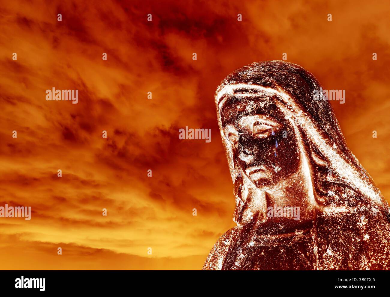 Crying statue of the virgin Mary against a burning sky Stock Photo - Alamy