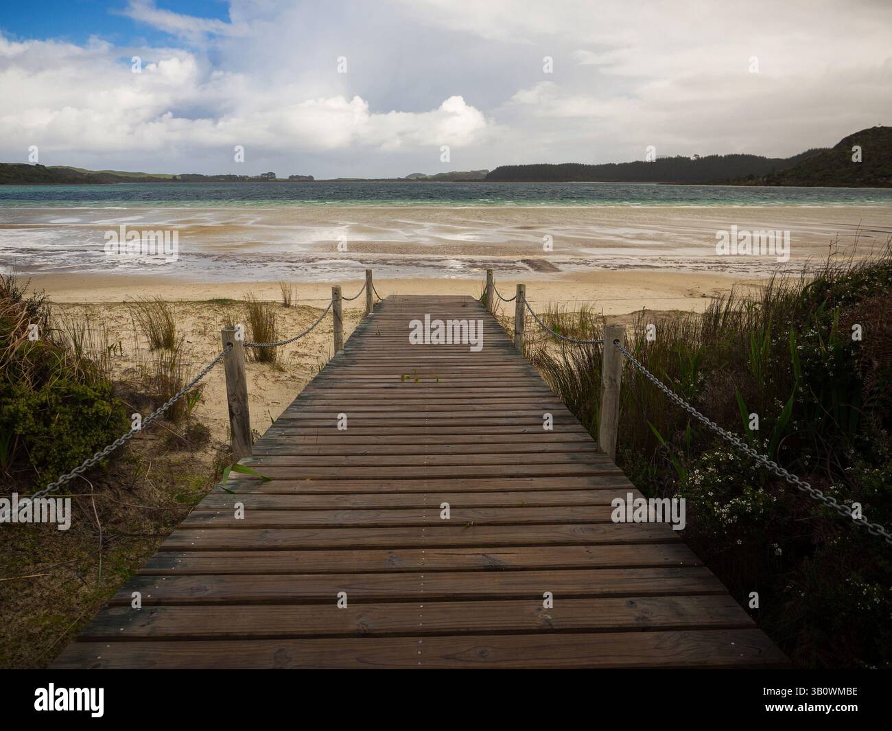 Wooden boardwalk walkway leading to white sand beach at blue turquoise ...