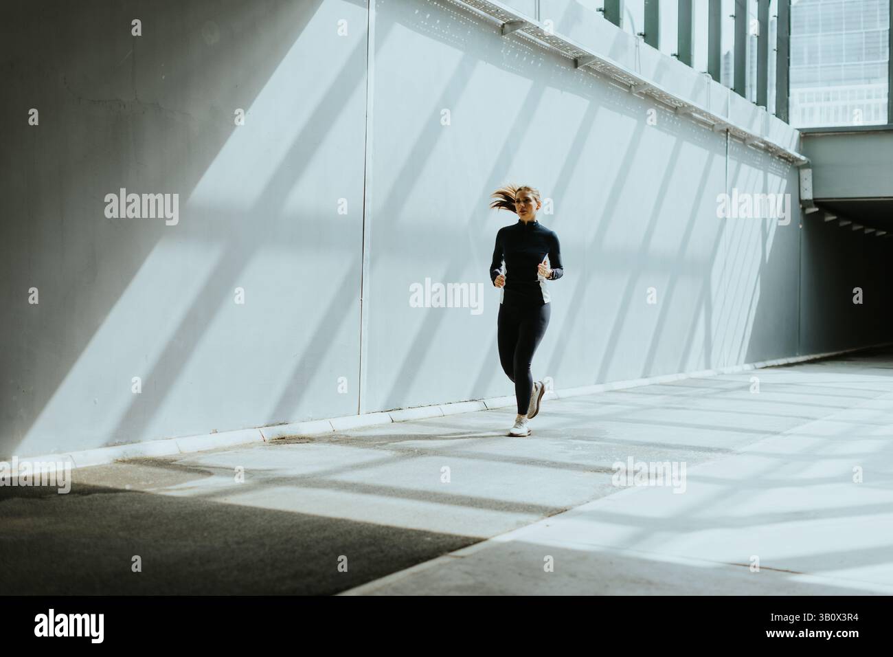 Sunlight filters through towering buildings as a jogger moves energetically along a lively urban ...