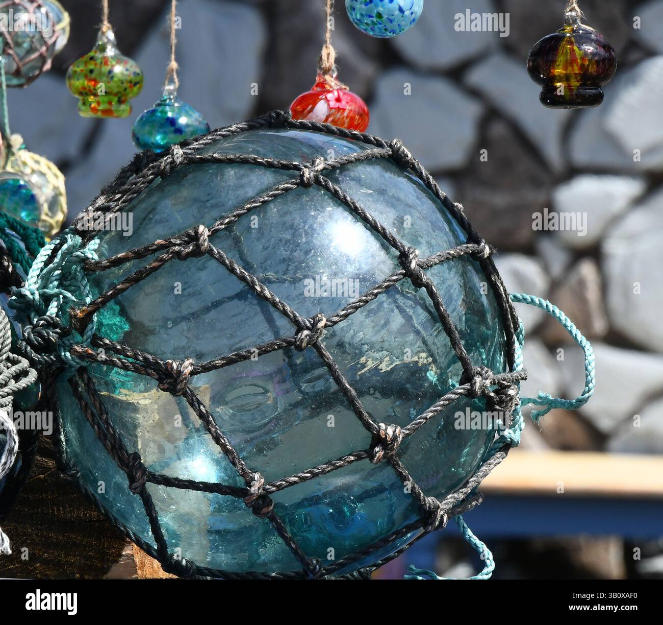 Large hand blown, glass float sits outside in the sunshine. Glass is ...