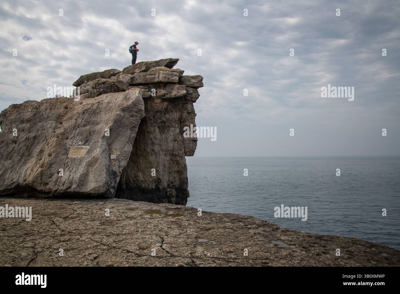 A lone figure stands on Pulpit rock looking out to sea Stock Photo - Alamy