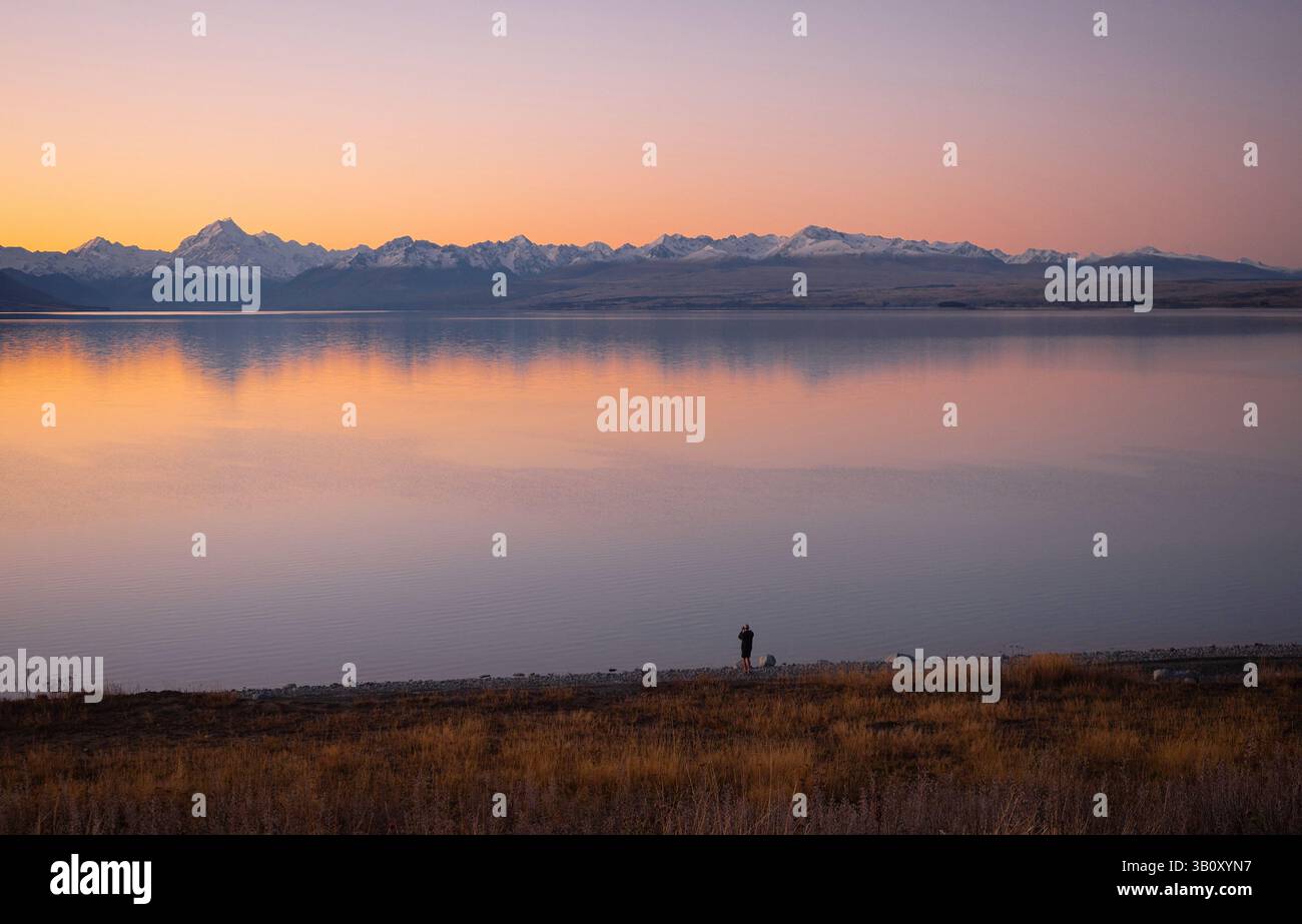 Tourist on lakeshore taking a photo of Mount Cook Aoraki mountain ...