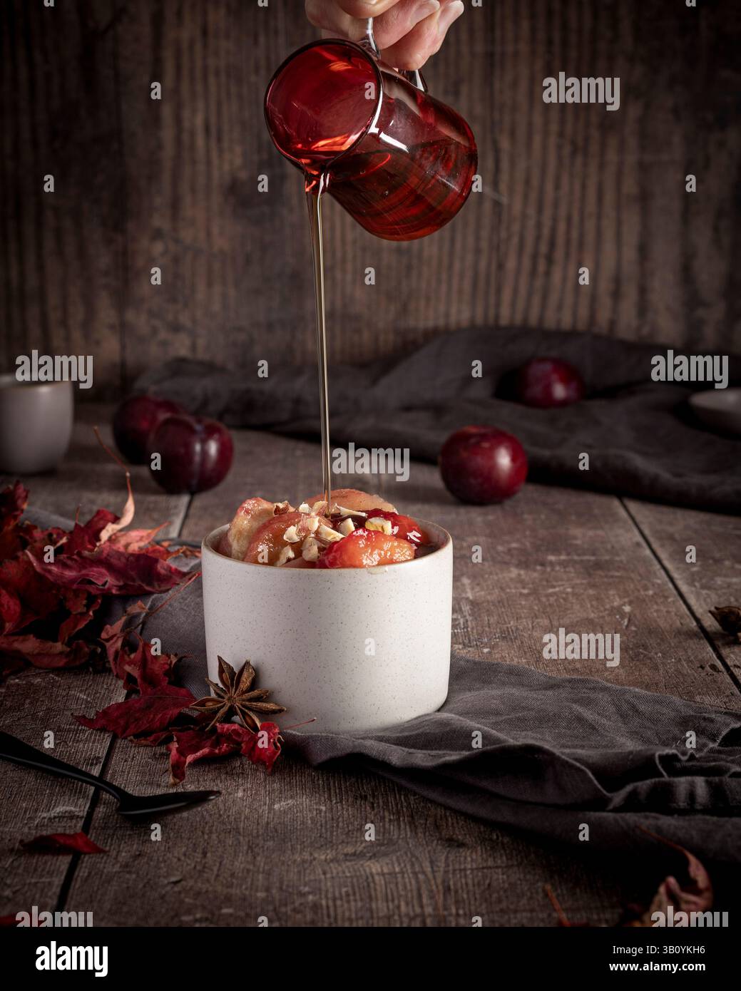 Baked Autumn fruits with chopped nuts and maple syrup, with a hand ...