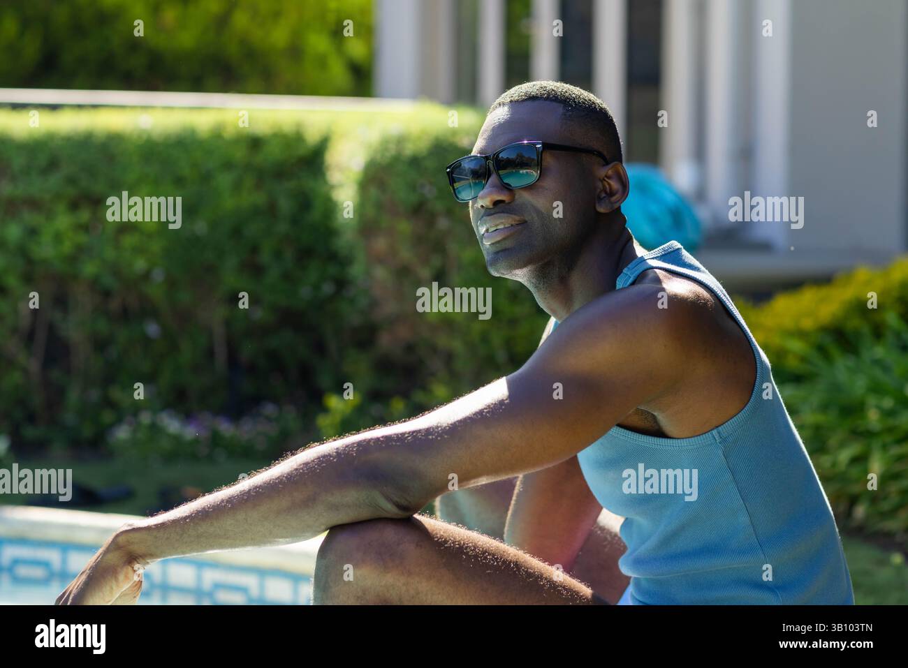 Sitting African American man staring into distance at pool edge, with ...