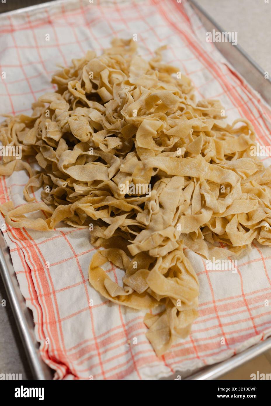 Fresh pasta is spread out on a cloth to dry before cooking, showcasing ...