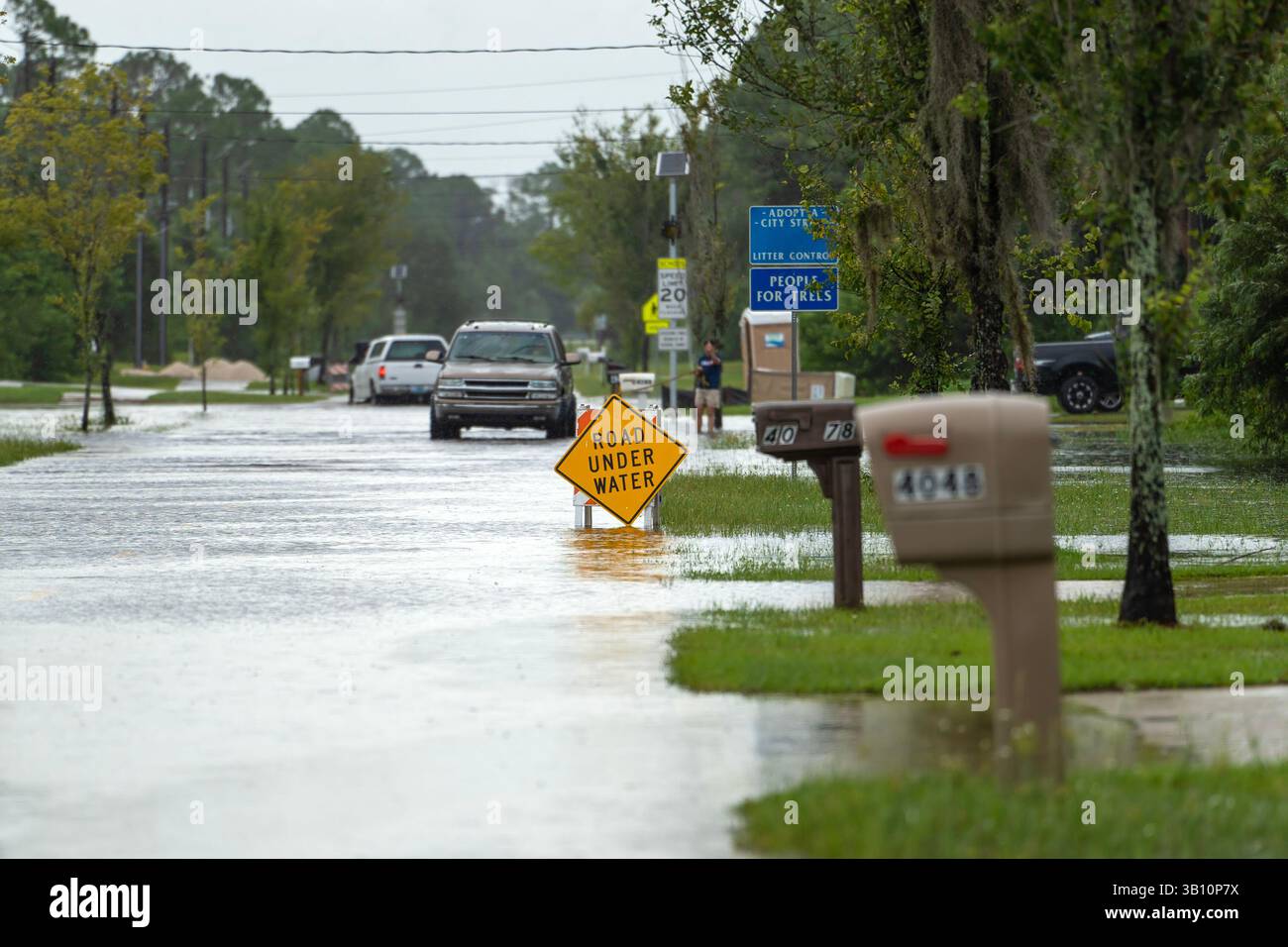 Flooded street in Florida after hurricane rainfall with road closed signs blocking driving of ...