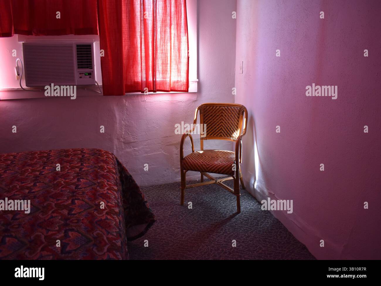Wicker chair in a cozy motel room interior with soft light from the ...