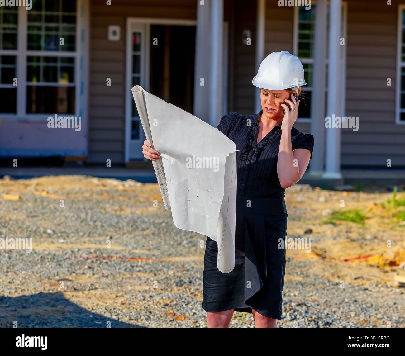 A young female construction supervisor studies house blueprints on-site ...