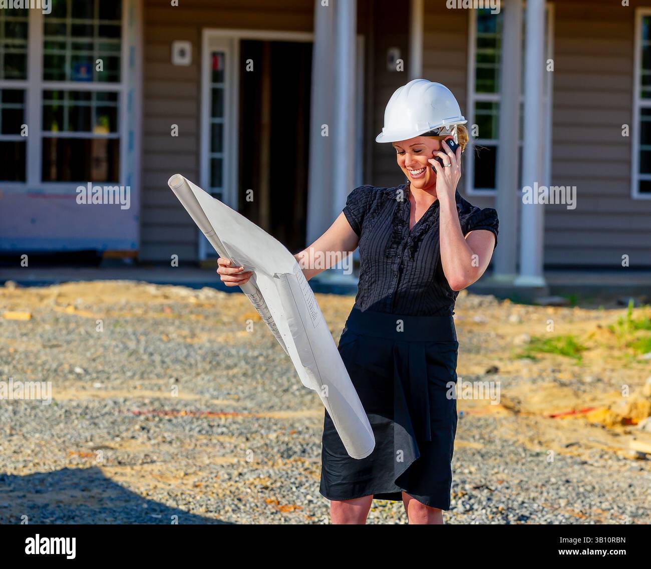 A young female construction supervisor studies house blueprints on-site ...