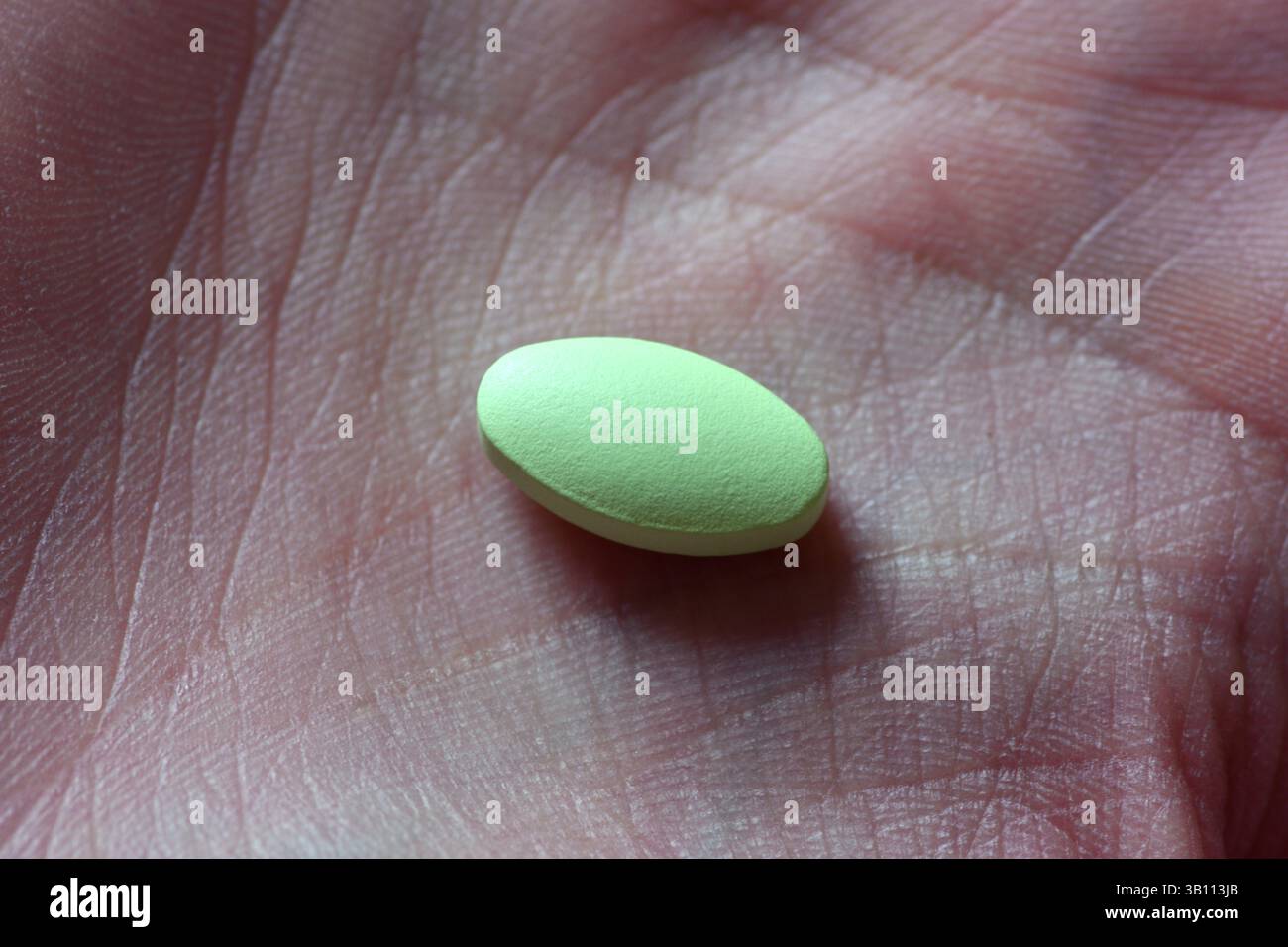 Green pill in the palm close up macro top view Stock Photo - Alamy