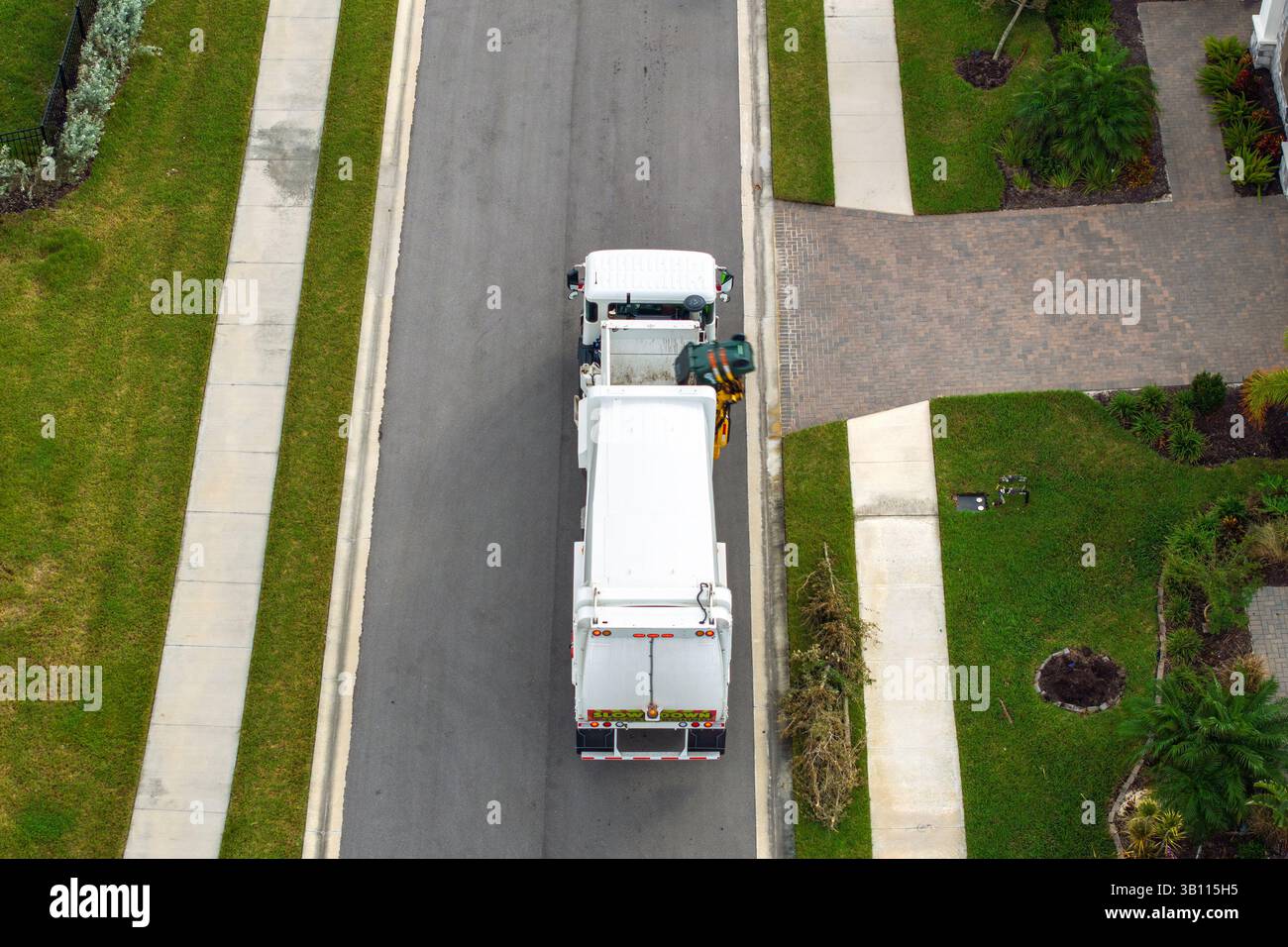 Trash truck picking up garbage bins on Florida city street curbside ...