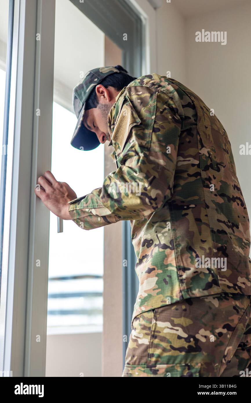 vertical Sad soldier in camouflage uniform leaning against a window at ...