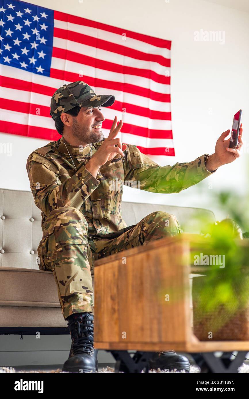 Happy american soldier in camouflage uniform sitting on sofa making ...