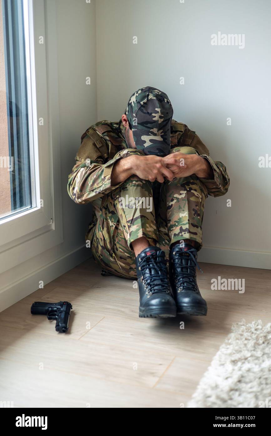 Young soldier in camouflage uniform sitting on the floor, head down ...