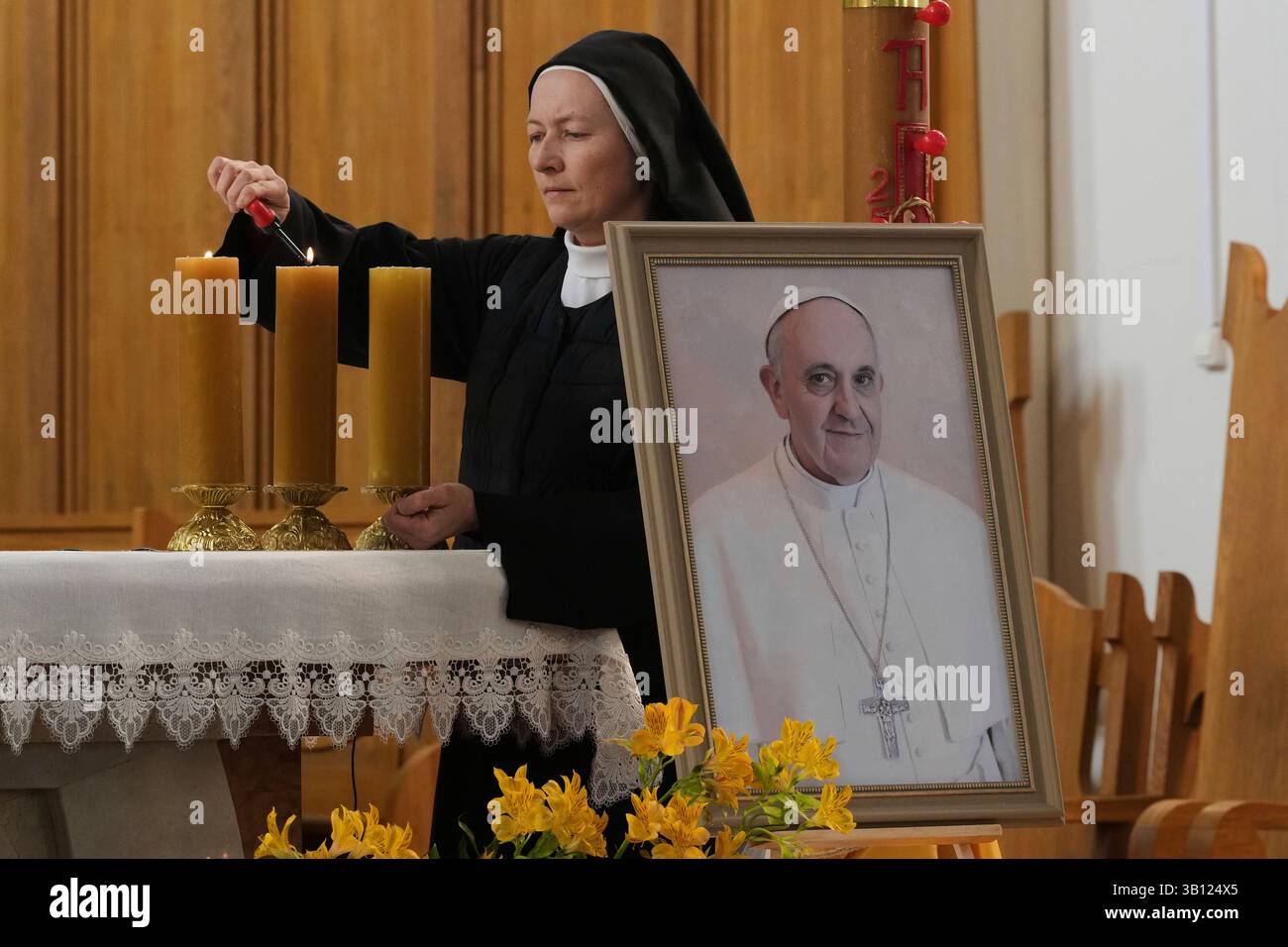 A nun lights candles prior to a mass to commemorate the late Pope ...