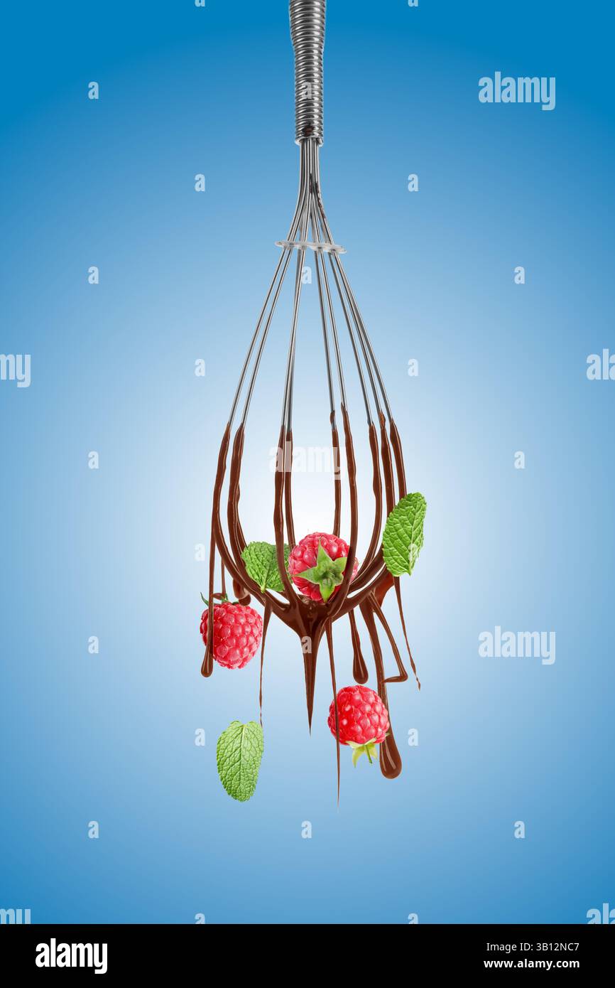 Chocolate cream dripping from whisk and falling raspberries on blue ...