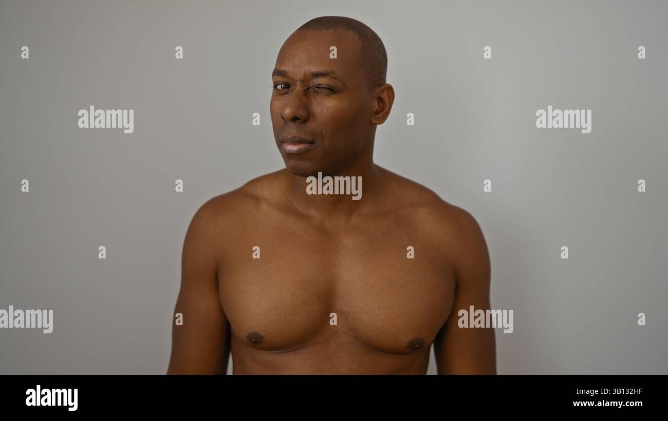 Young man winking while standing against a white background, displaying ...