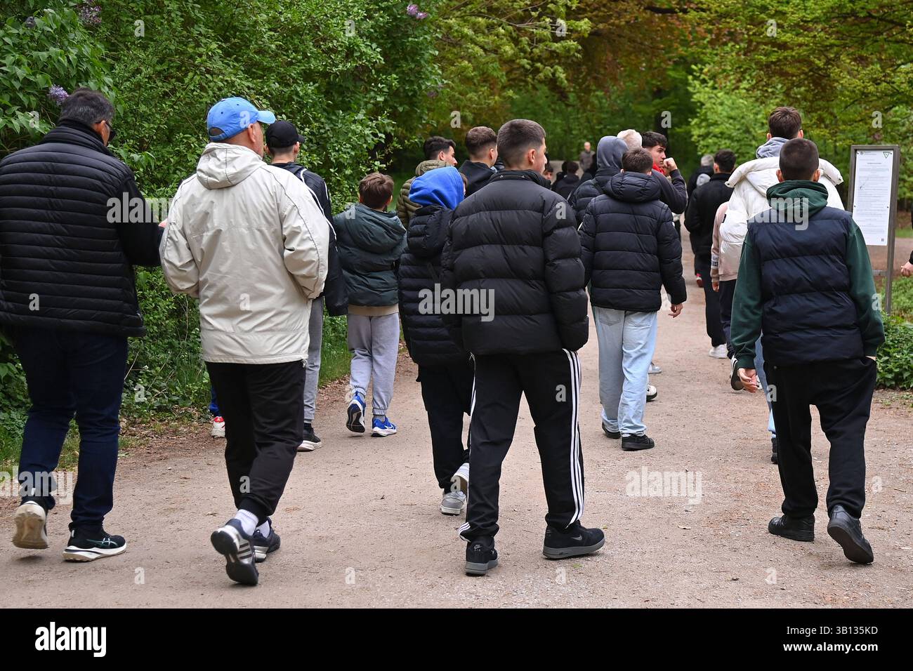 Eine Gruppe junger auslaendischer Maenner geen durch einen Park. *** A ...