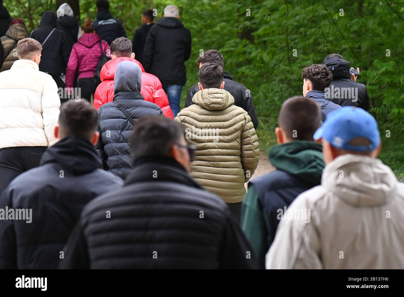 Eine Gruppe junger auslaendischer Maenner geen durch einen Park. *** A ...