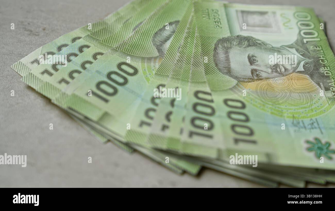 Chilean banknotes of 1000 pesos stacked on a concrete surface ...