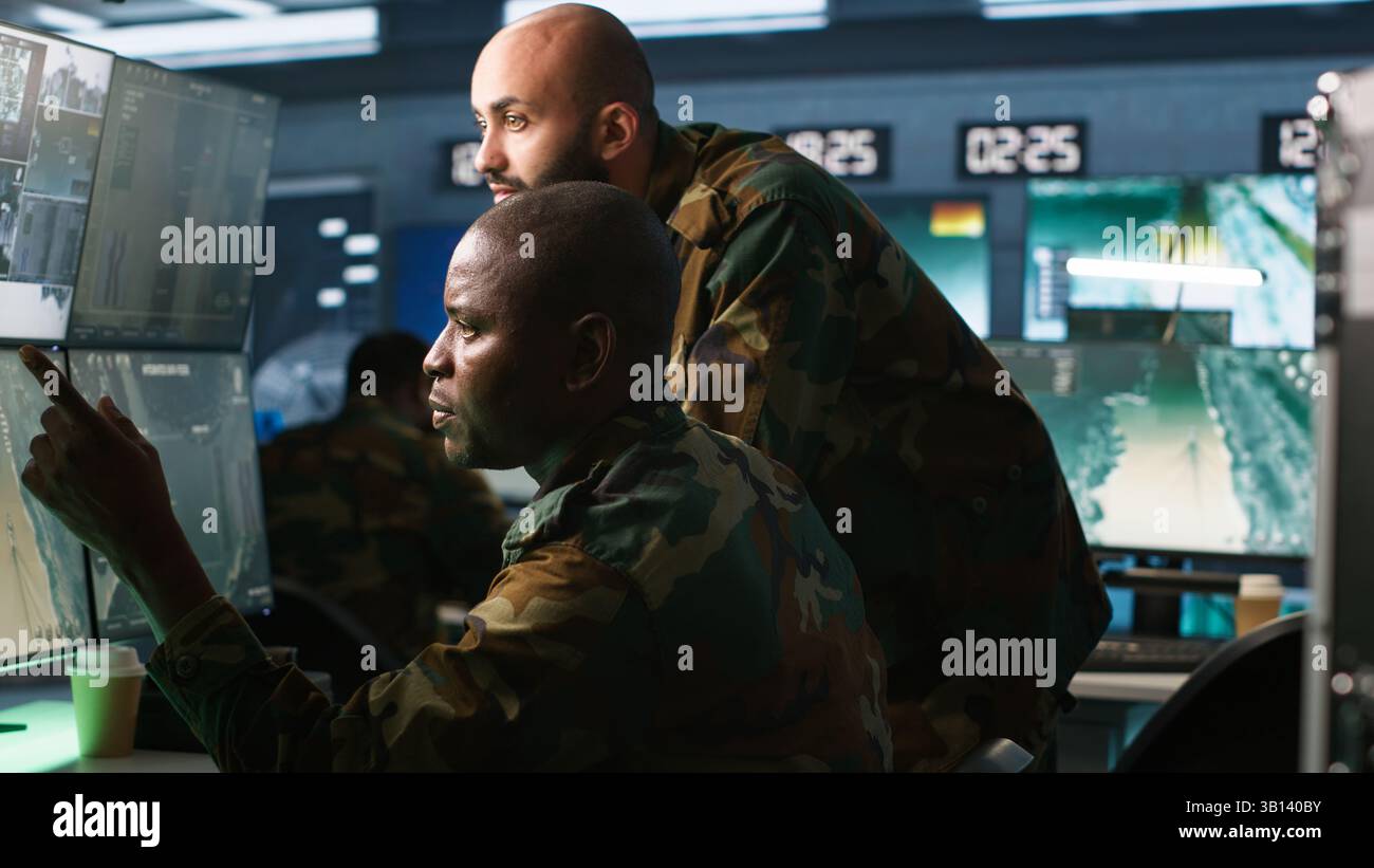 Air force officers performing tactical level reconnaissance in command post, looking at monitors ...