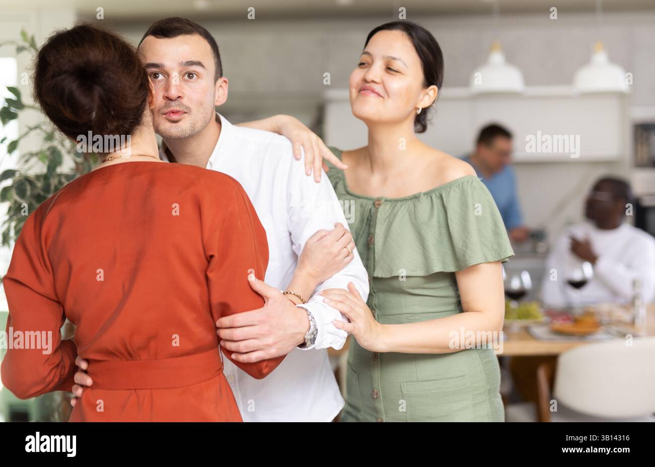 Man hosting and kissing female guest arriving for friendly dinner Stock ...