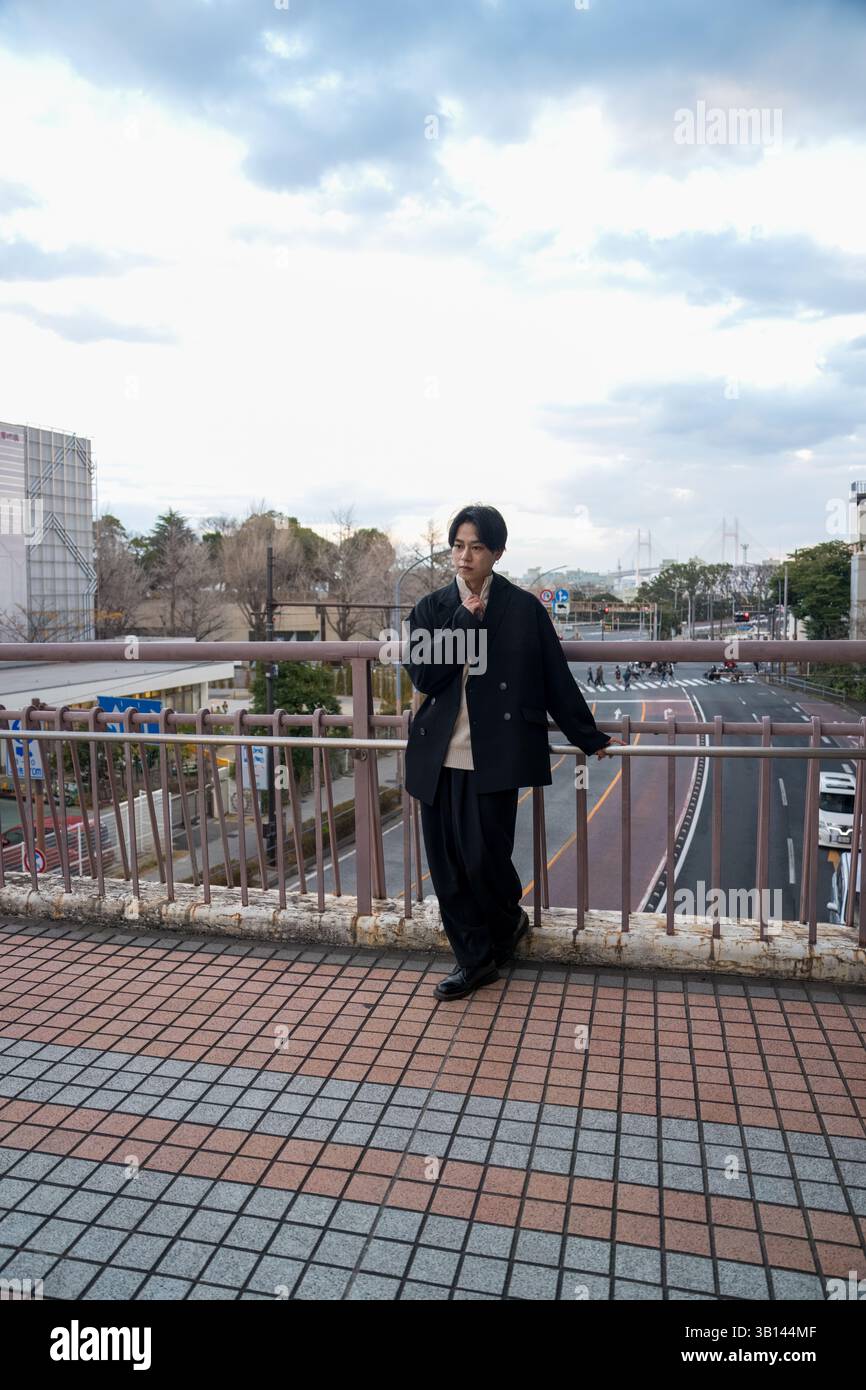 A Japanese man in his twenties stands at a pedestrian crossing in ...