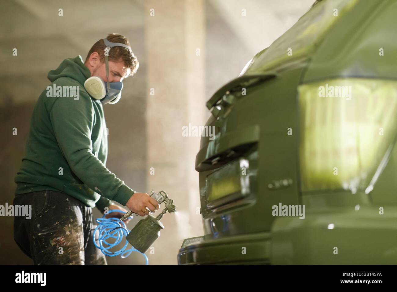 A skilled painter focuses on applying a smooth coat of green paint to a ...