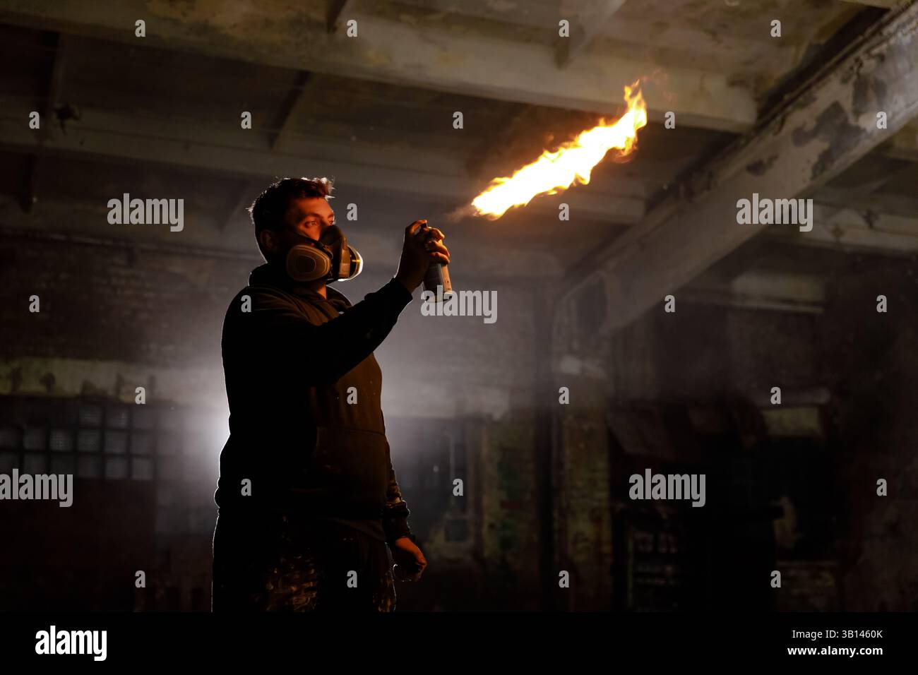 An artist wearing a gas mask ignites a spray can to create a ...