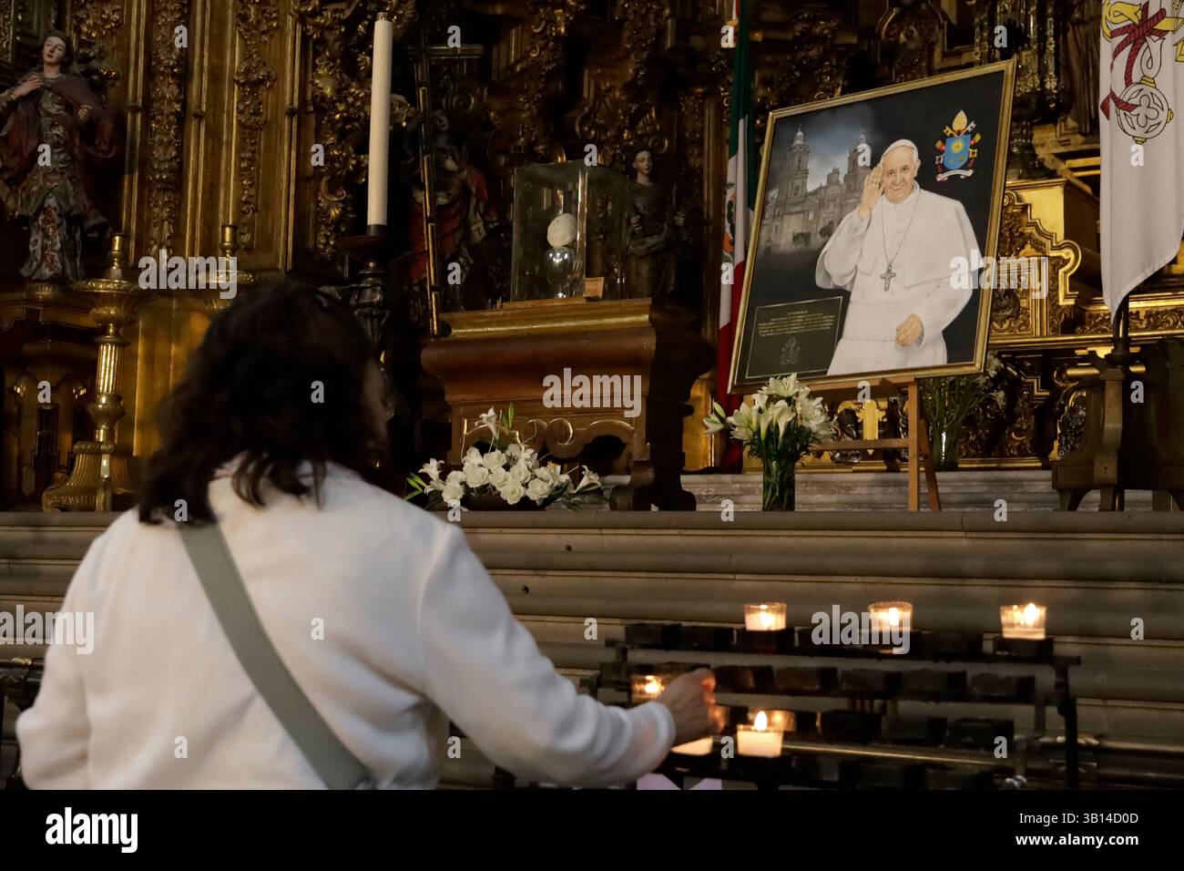 A Catholic faithful lights a candle in front of an image of Pope Francis in an altar during a ...