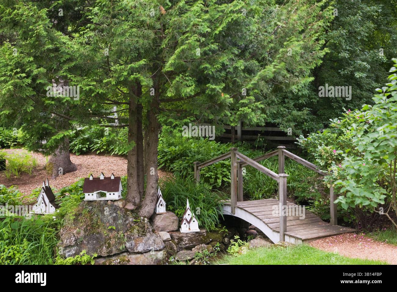 Wooden footbridge and white painted wood and rusted metal birdhouses ...