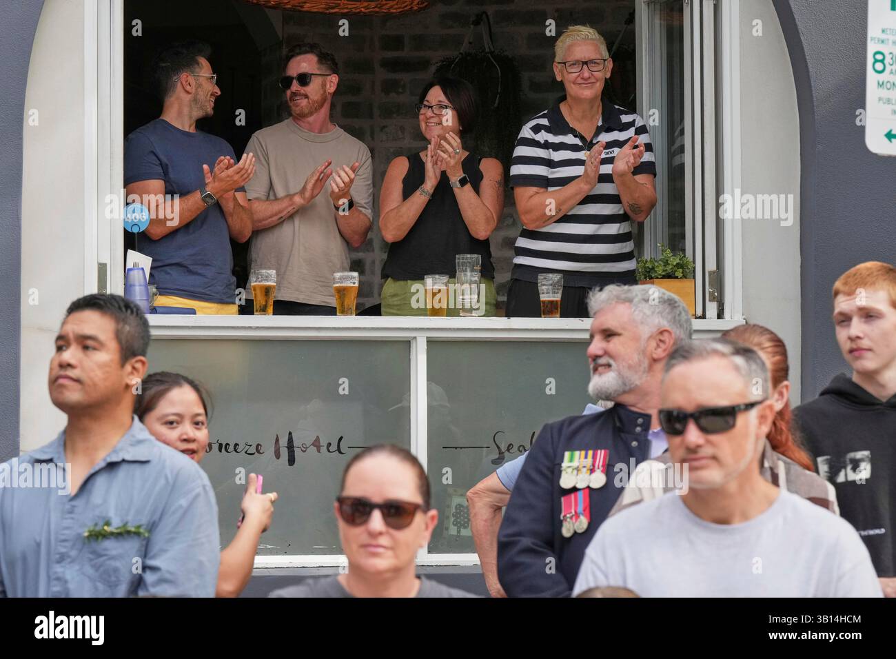 People react as they watch the Anzac Day commemorations in Nelson Bay ...