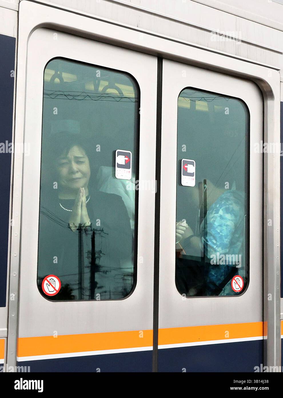 A train passenger prays for the victims of a train derailment accident 20 years ago in Amagasaki ...
