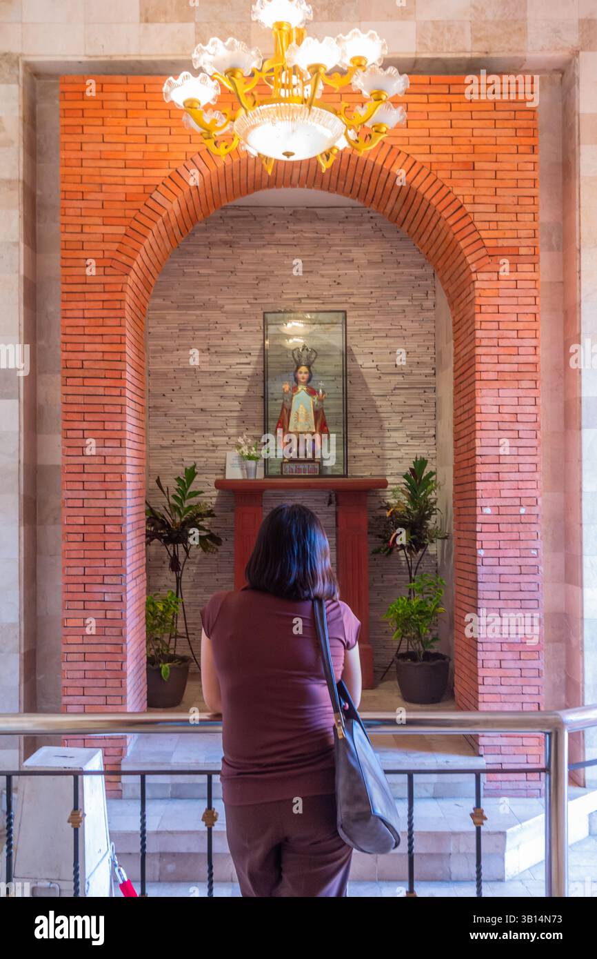 A Filipino woman offers a prayer to the image of the Sto Niño de Kalibo ...