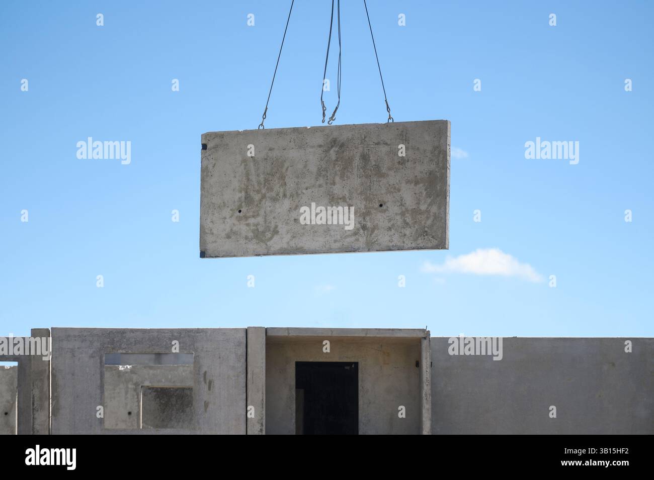 Close-up of concrete slab hanging on crane hook above building on ...