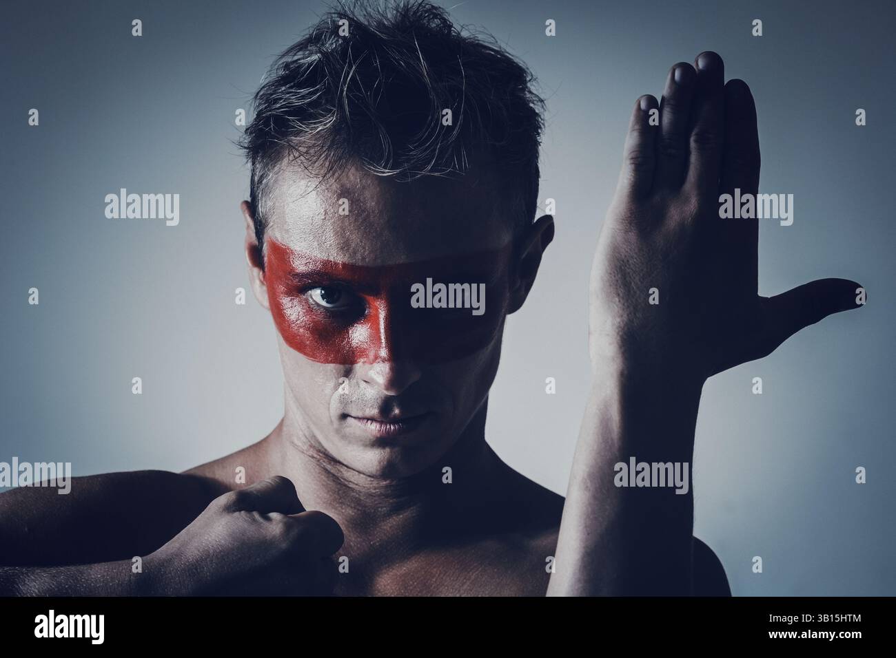 Athletic fighter in red mask demonstrating boxing stance with punching ...