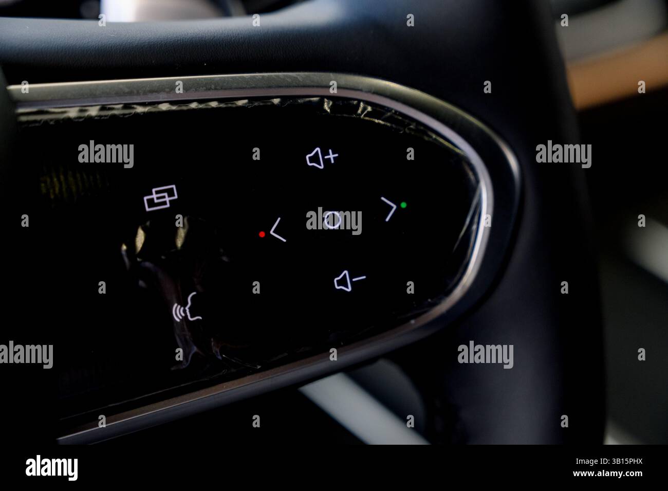 A close-up of a modern car's steering wheel, made of smooth black ...